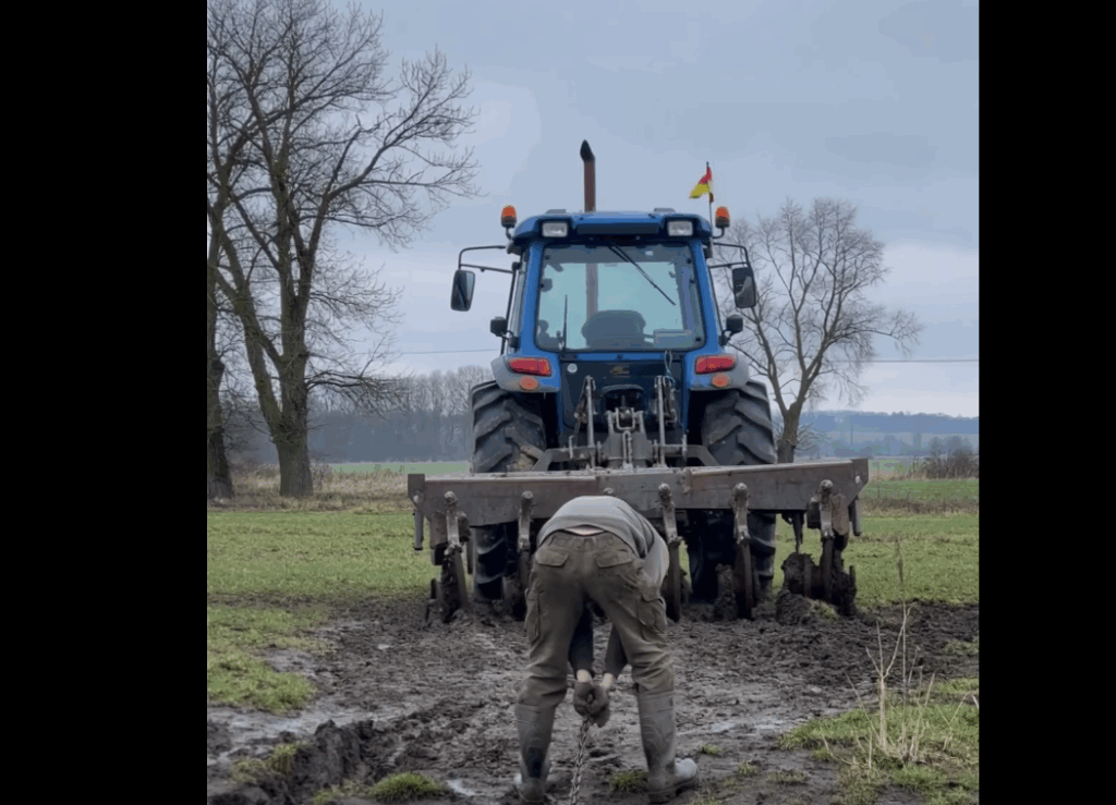 Tractoristul ara pământul lângă râu, iar plugul s-a agățat de un lanț ...